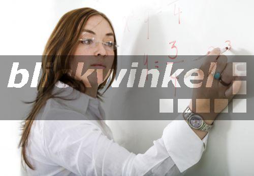 blickwinkel - junge Mathelehrerin rechnet an der Tafel vor - female ...