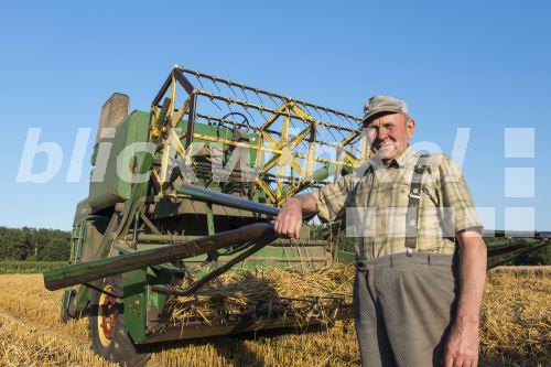blickwinkel - Bauer vor seinem alten Maehdrescher bei der Getreideernte ...